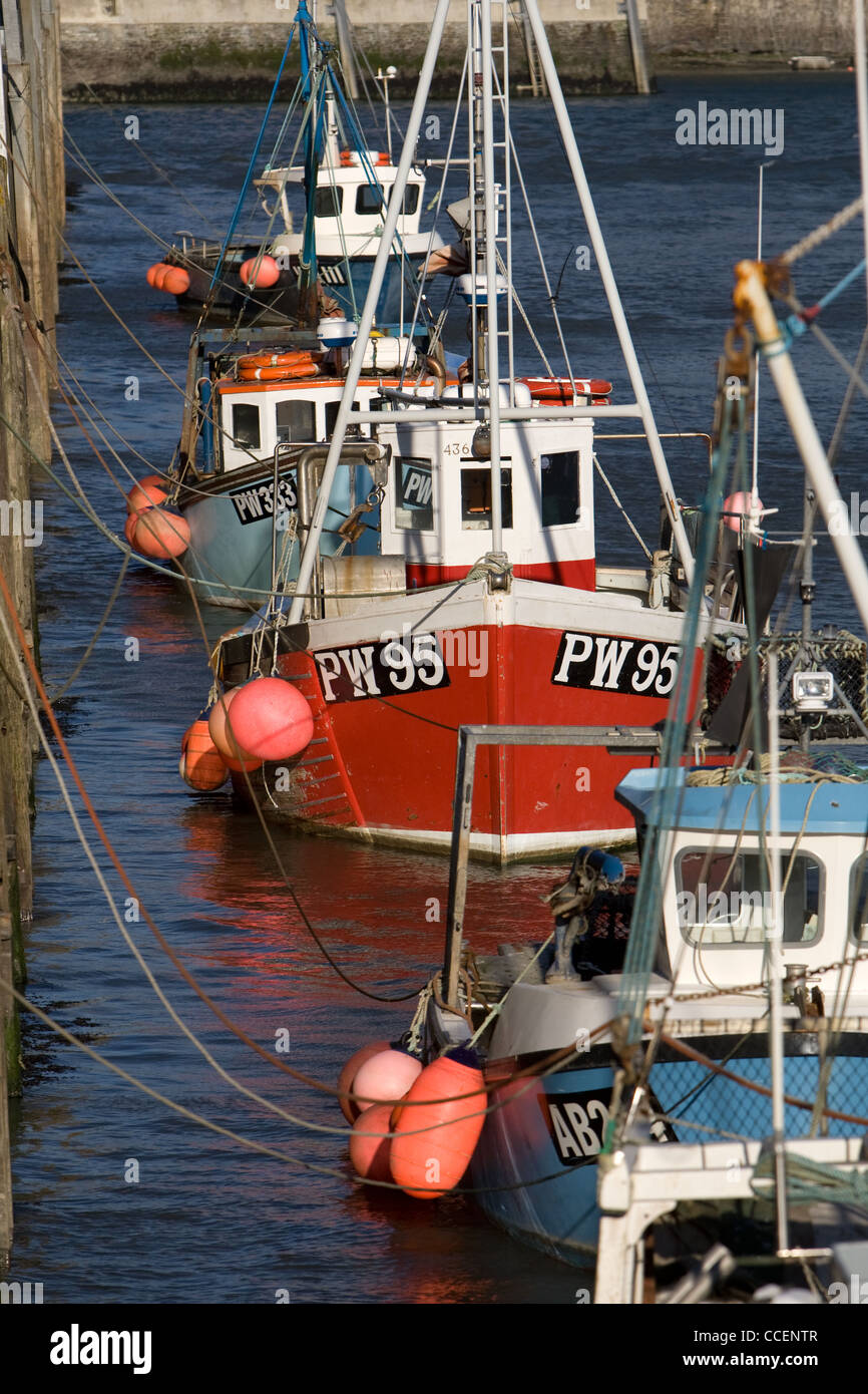 Moored fishing boats lined up against the harbour wall at Padstow ...