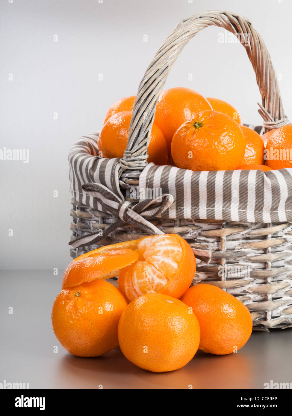 Basket and stack of fresh tangerines on silver background Stock Photo ...