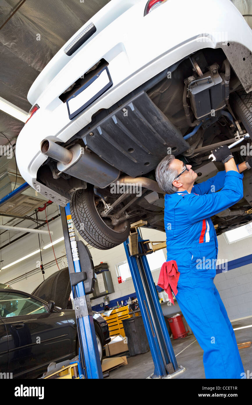 Low angle view of senior mechanic working under car Stock Photo - Alamy