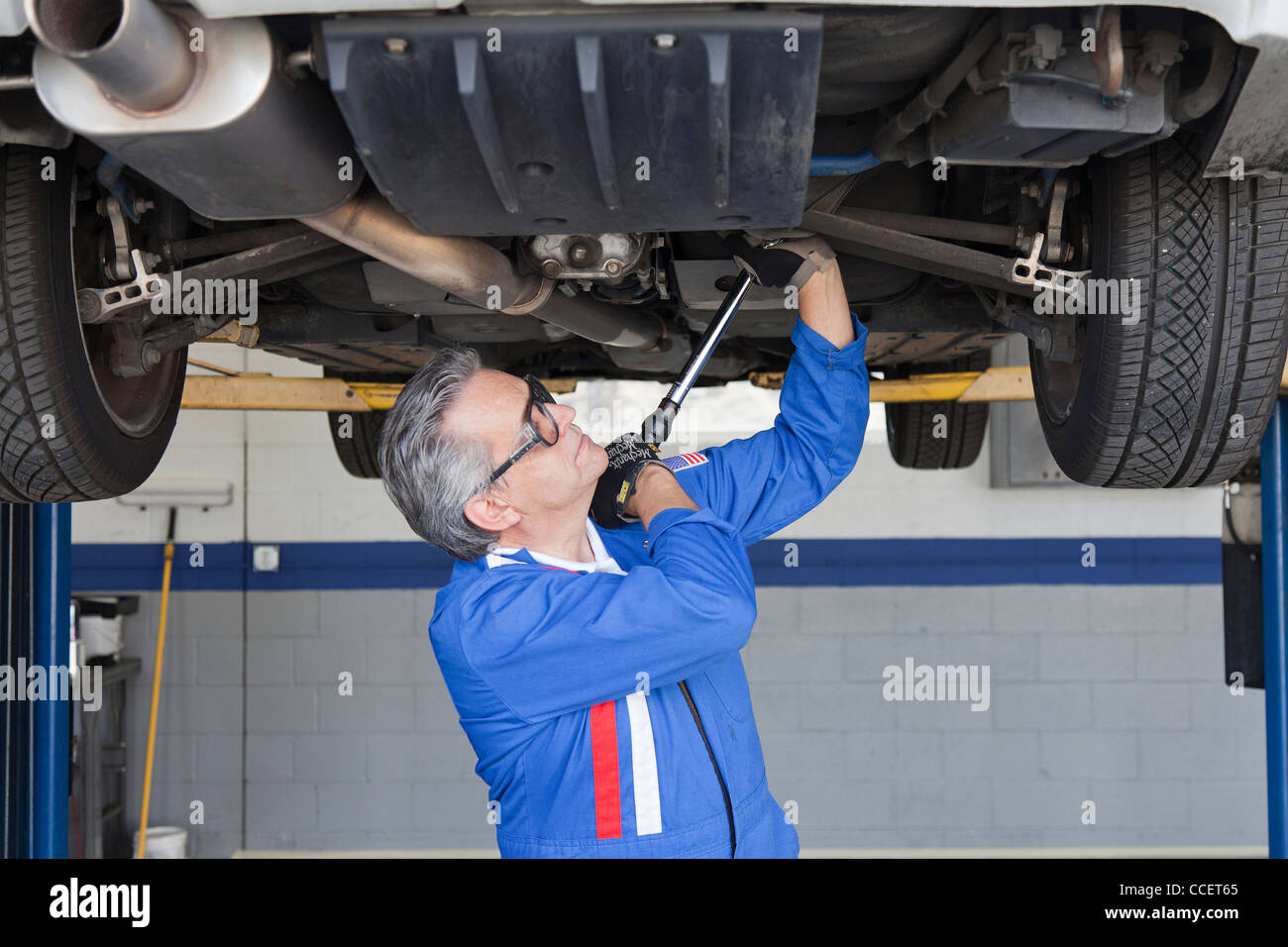 Car mechanics working below a car using a monkey wrench Stock Photo - Alamy
