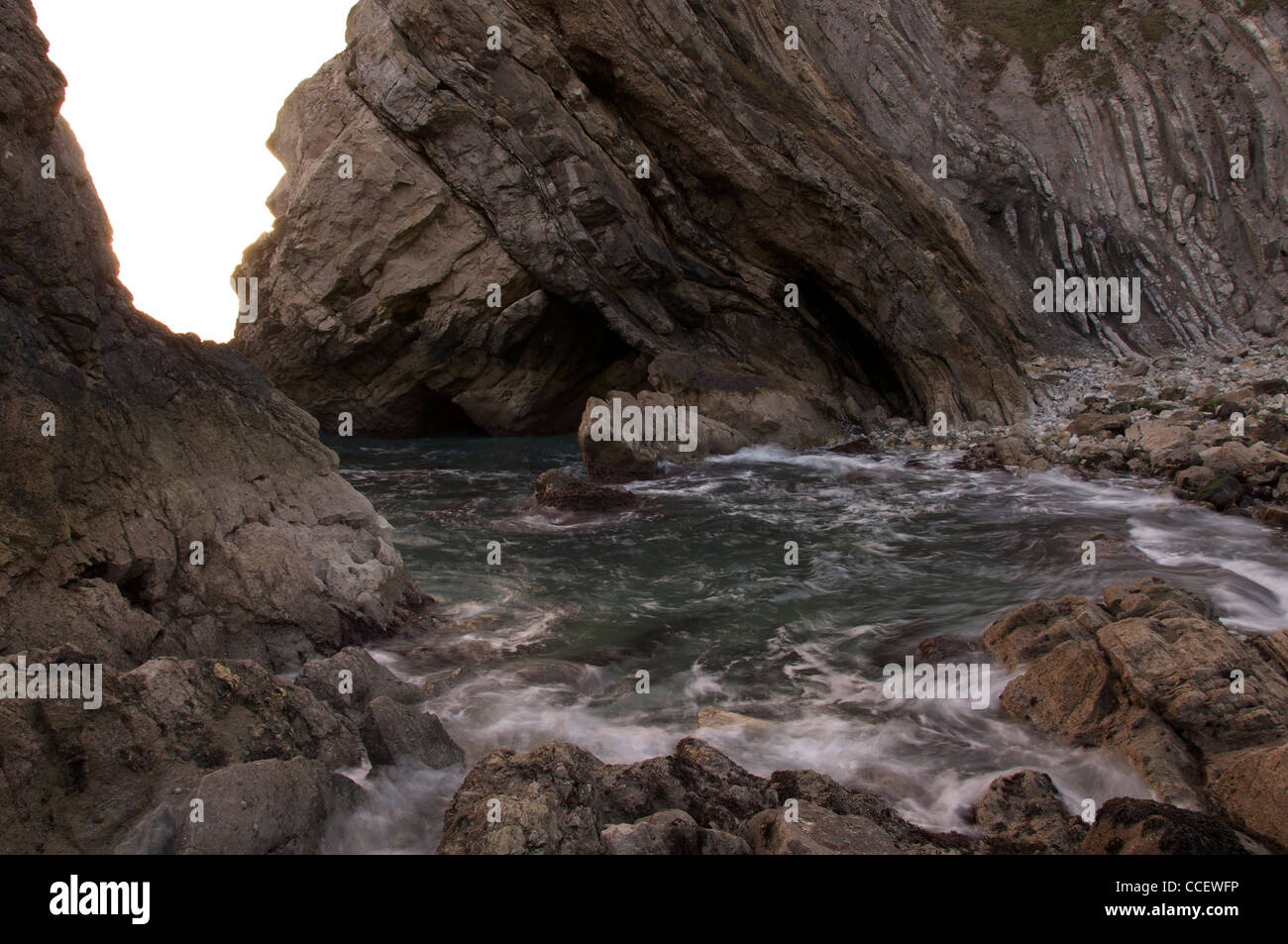 Waves surge through a rocky inlet into Stair Hole. The tilted rock ...