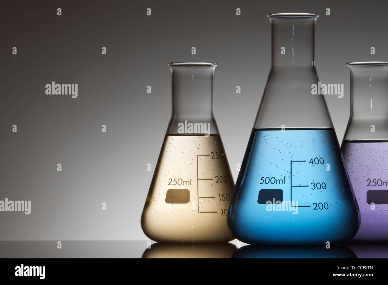three flasks with colored liquid and a white background Stock Photo - Alamy