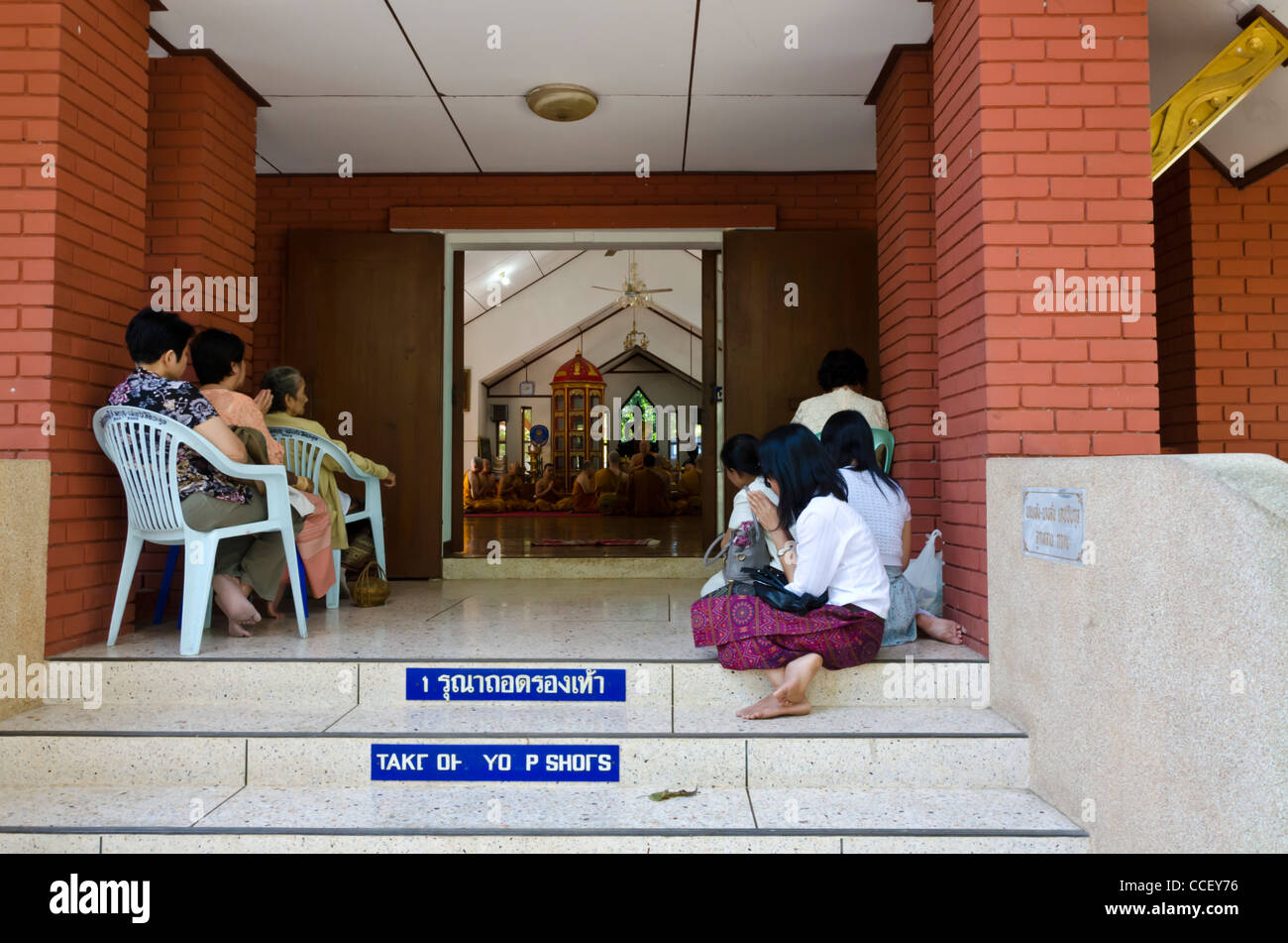 Relatives watch Buddhist monk initiation ceremony from porch of ...