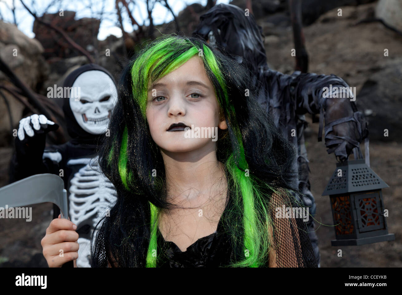 Portrait Of Girl Dressed Up As Witch While Her Friends Dressed Up In Skeleton Costume Stock