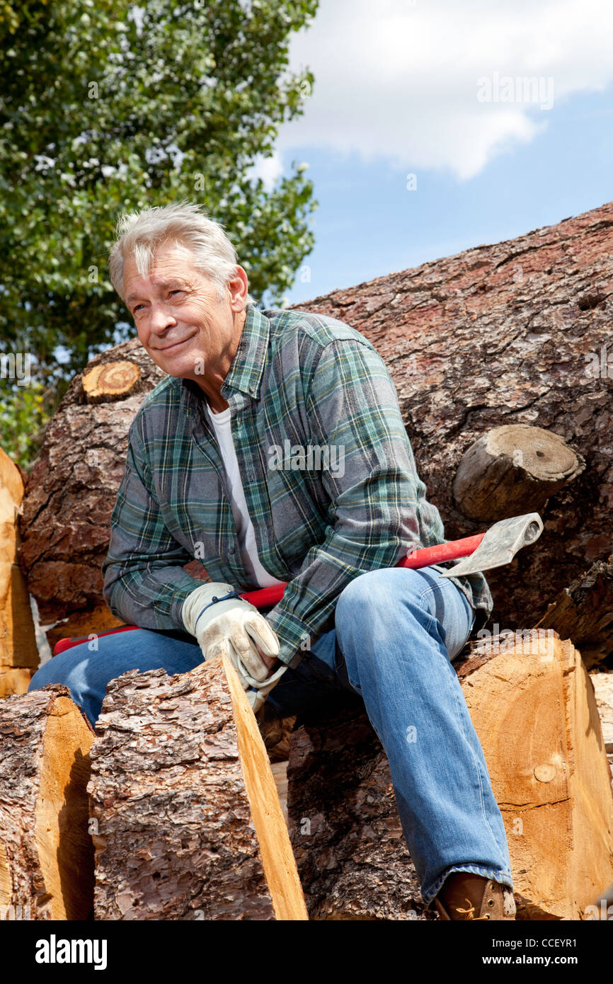Senior man sitting on wood logs with an axe Stock Photo - Alamy