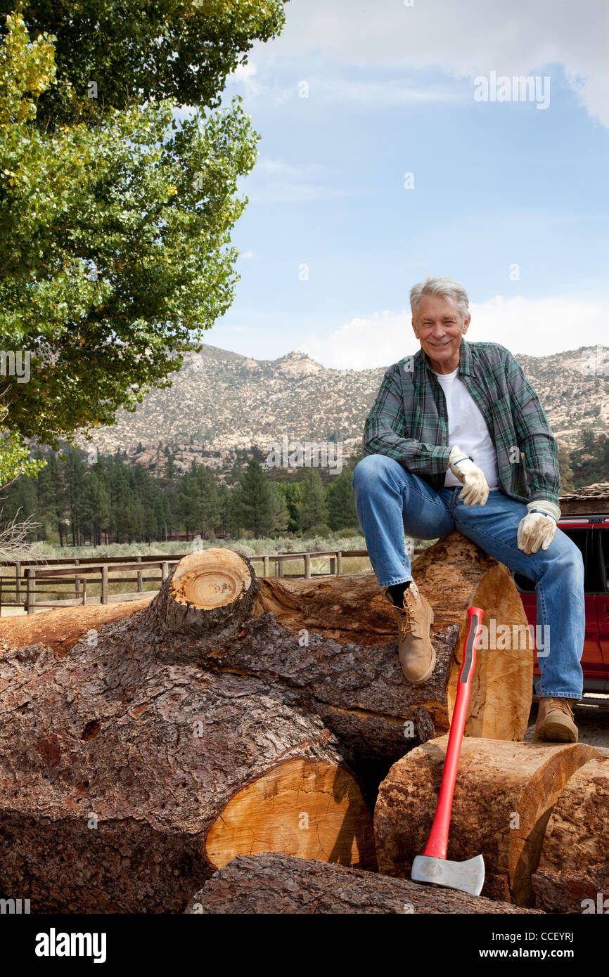 Man sitting on chopped tree trunk Stock Photo - Alamy