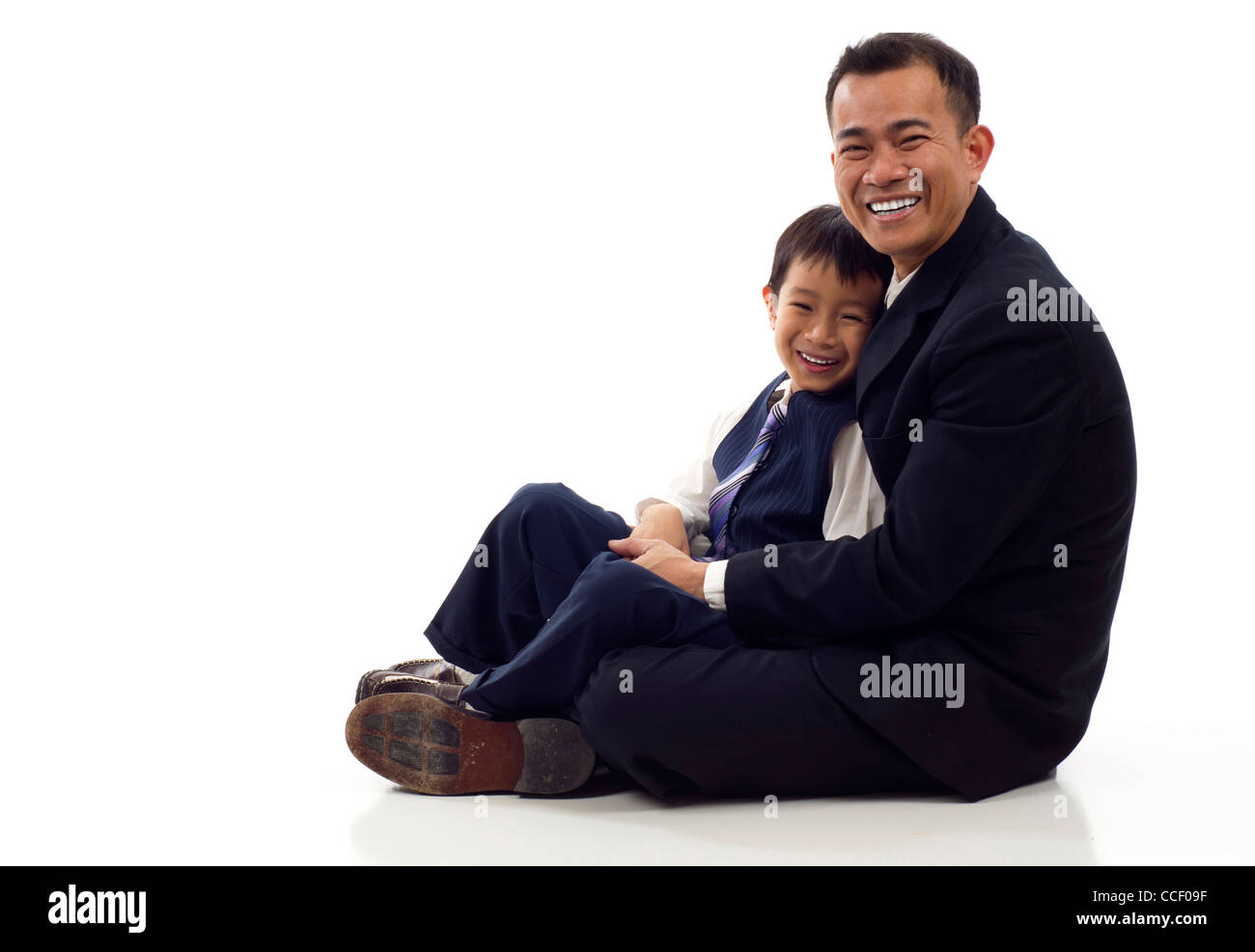 Portrait of a happy Asian father and son sitting together on white ...