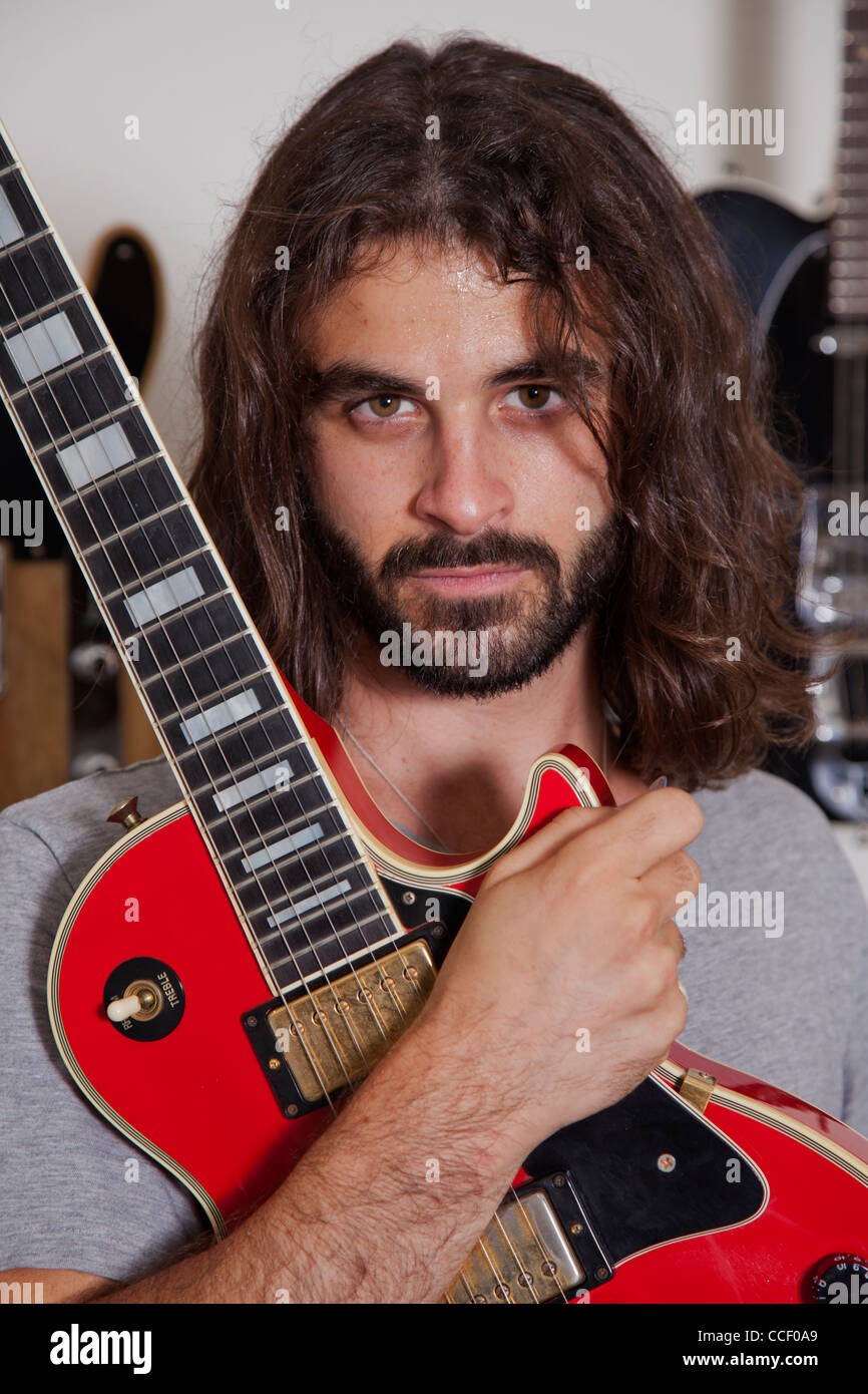 Portrait of serious young musician holding guitar Stock Photo - Alamy