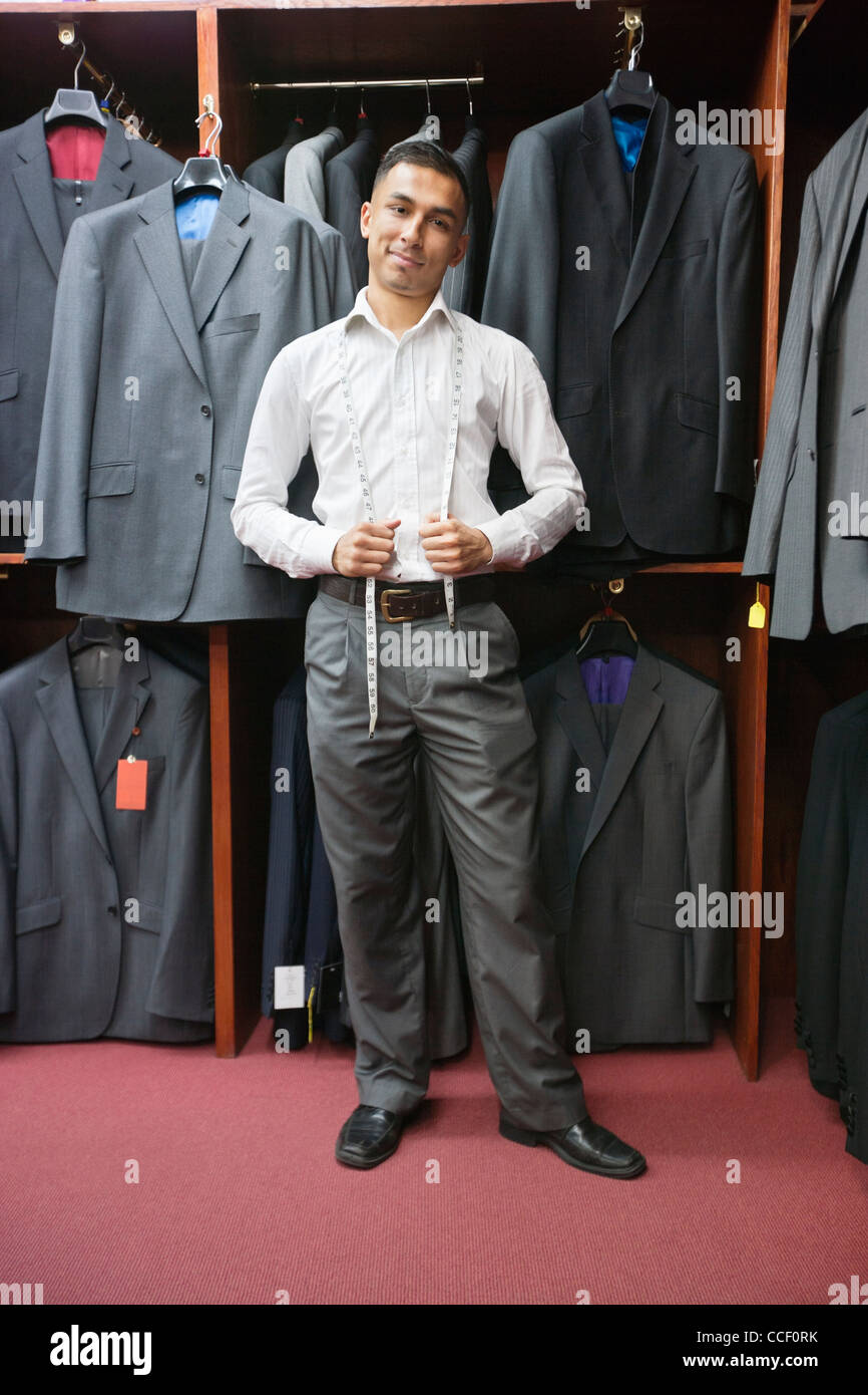 Portrait of young man posing with suits hanging in background Stock ...