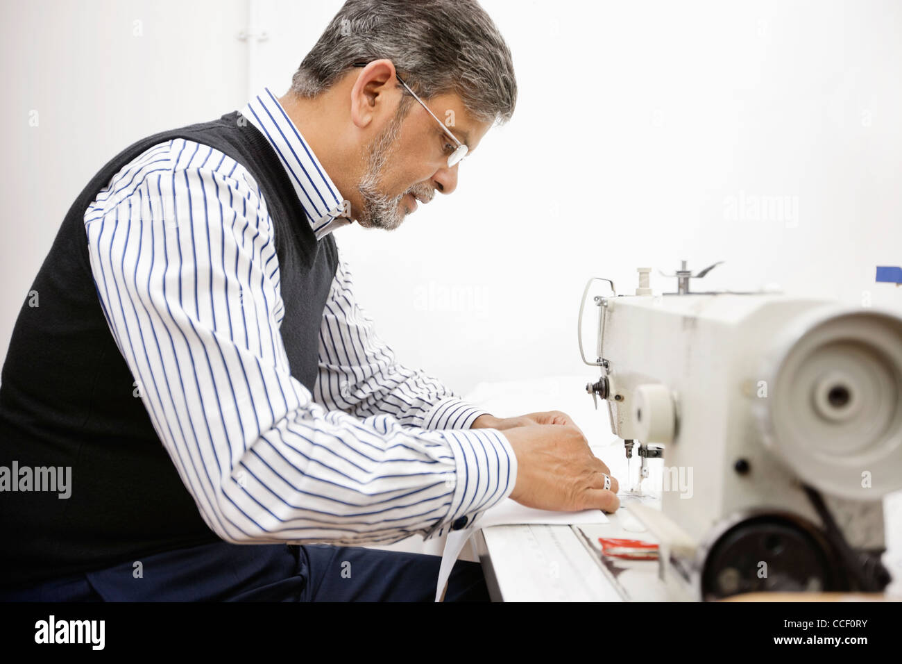 Profile of middle aged tailor using sewing machine Stock Photo - Alamy