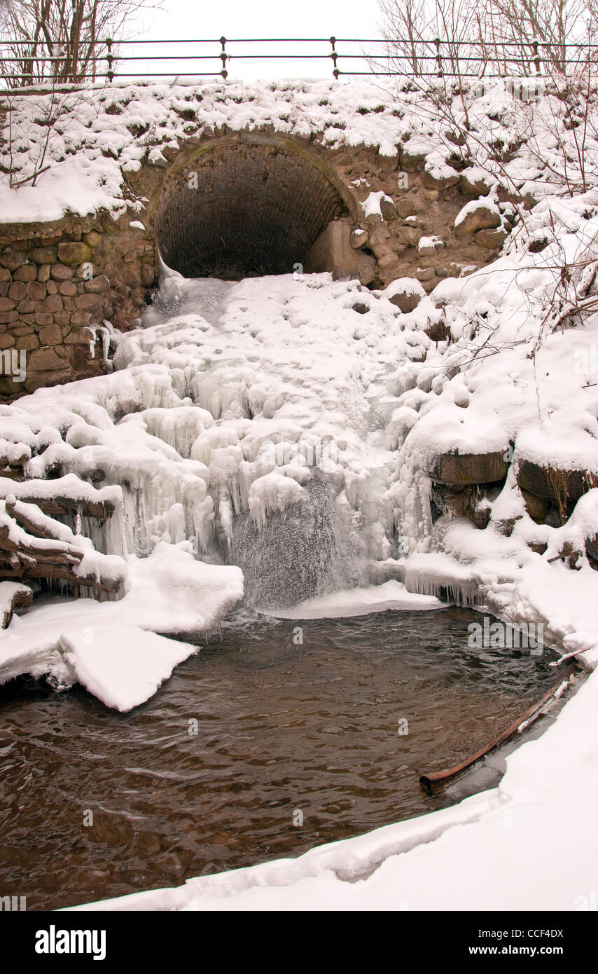 Stream water flow through arch waterfall ice icycles frozen in winter ...