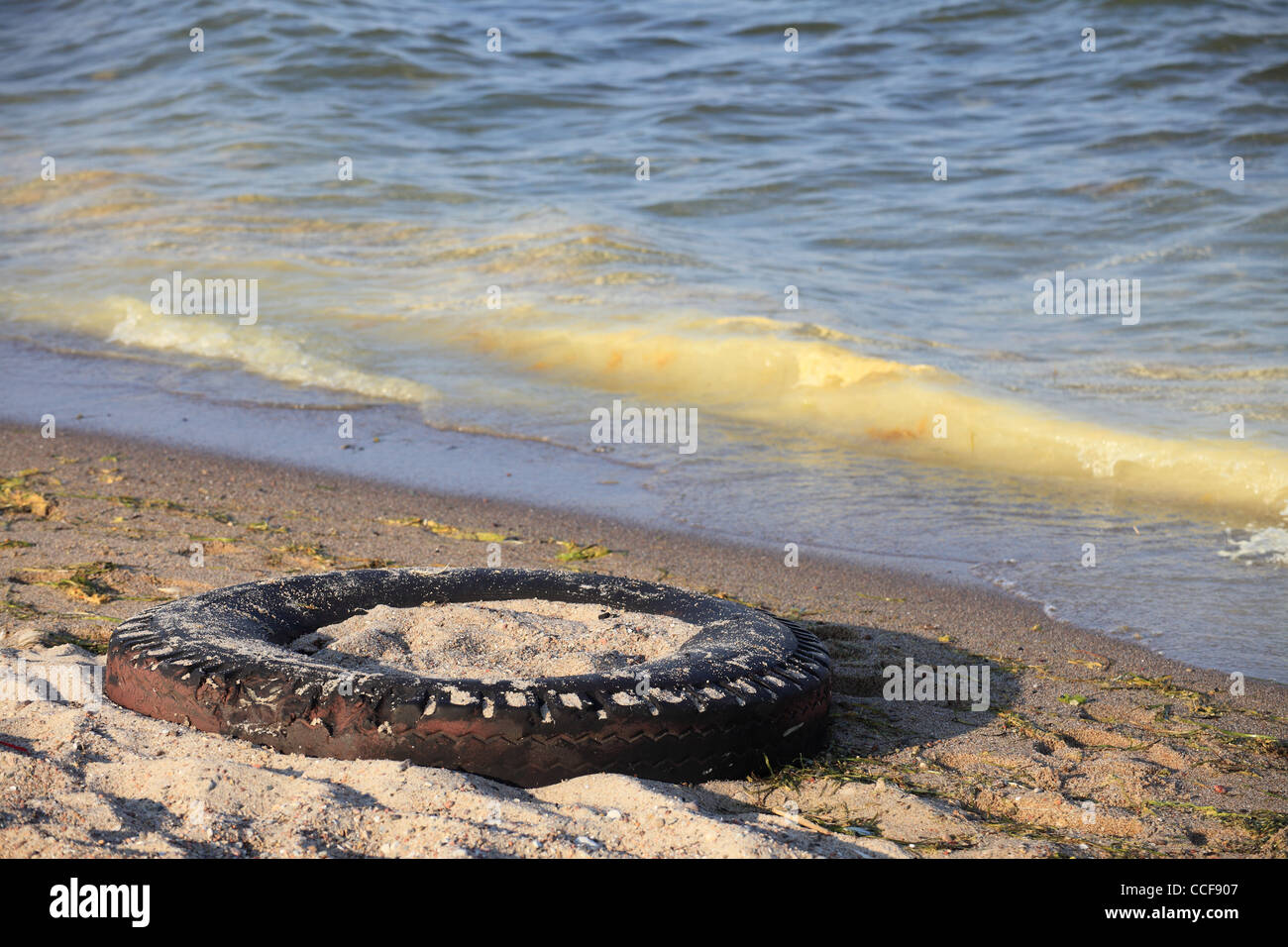 Tire on a beach - ecology environment Stock Photo - Alamy