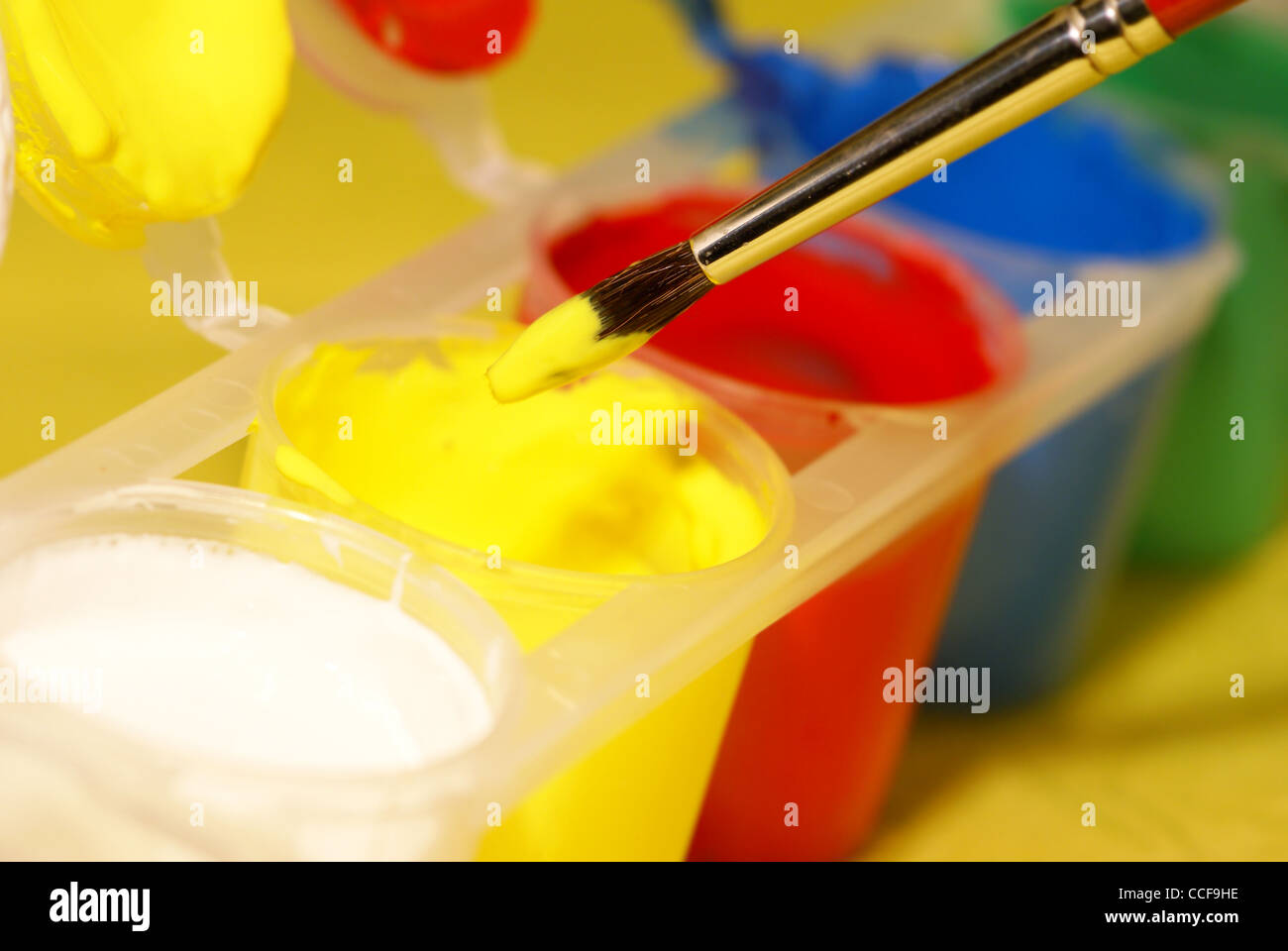 paintbrush diped into the yellow colour of watercolour set. Shallow DOF ...