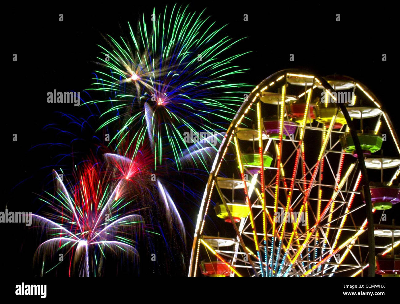 The carnival Ferris Wheel spins in the foreground as fireworks light ...