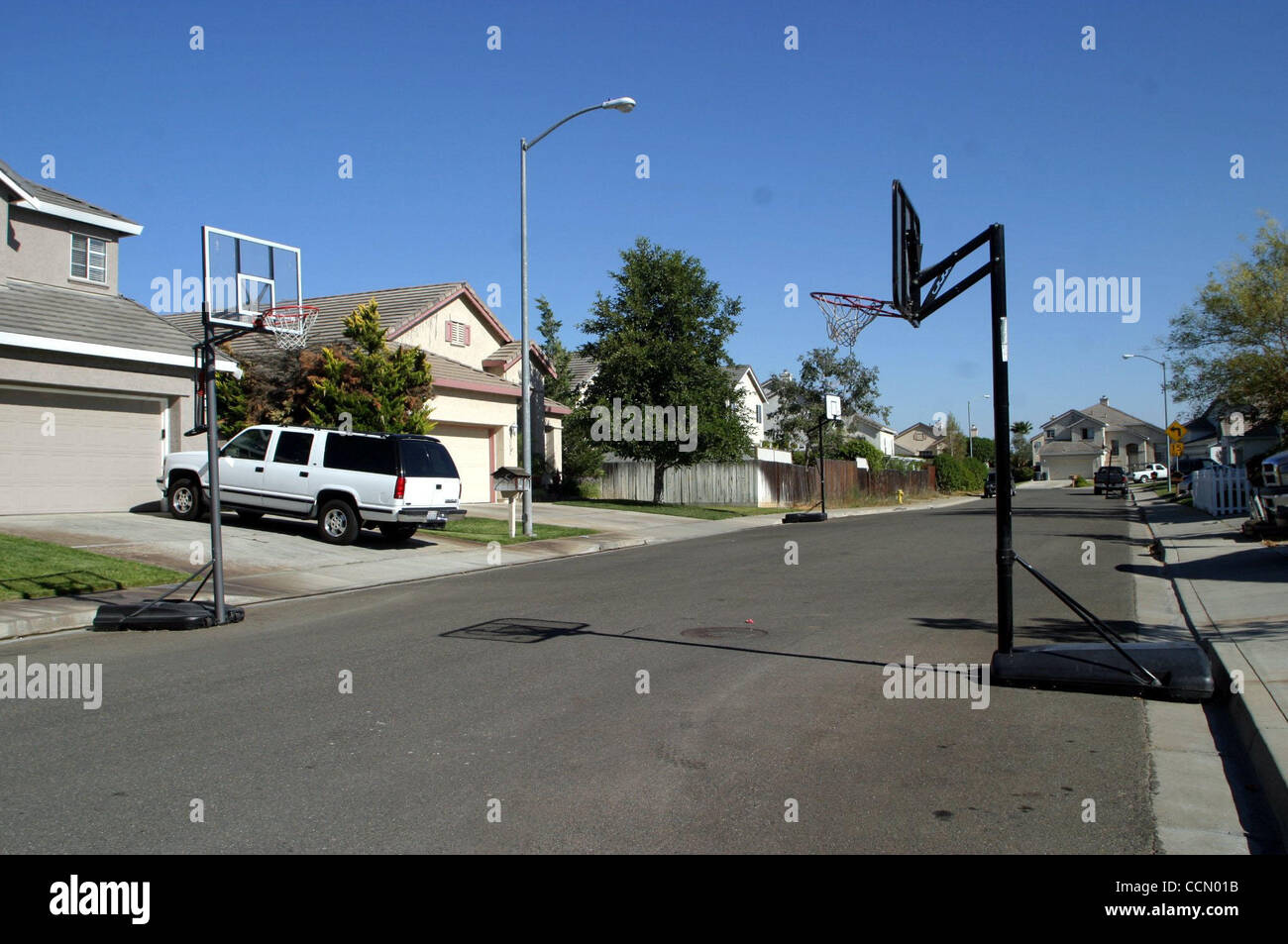 Portable basketball hoops line a street in Discovery Bay, Calif. on ...