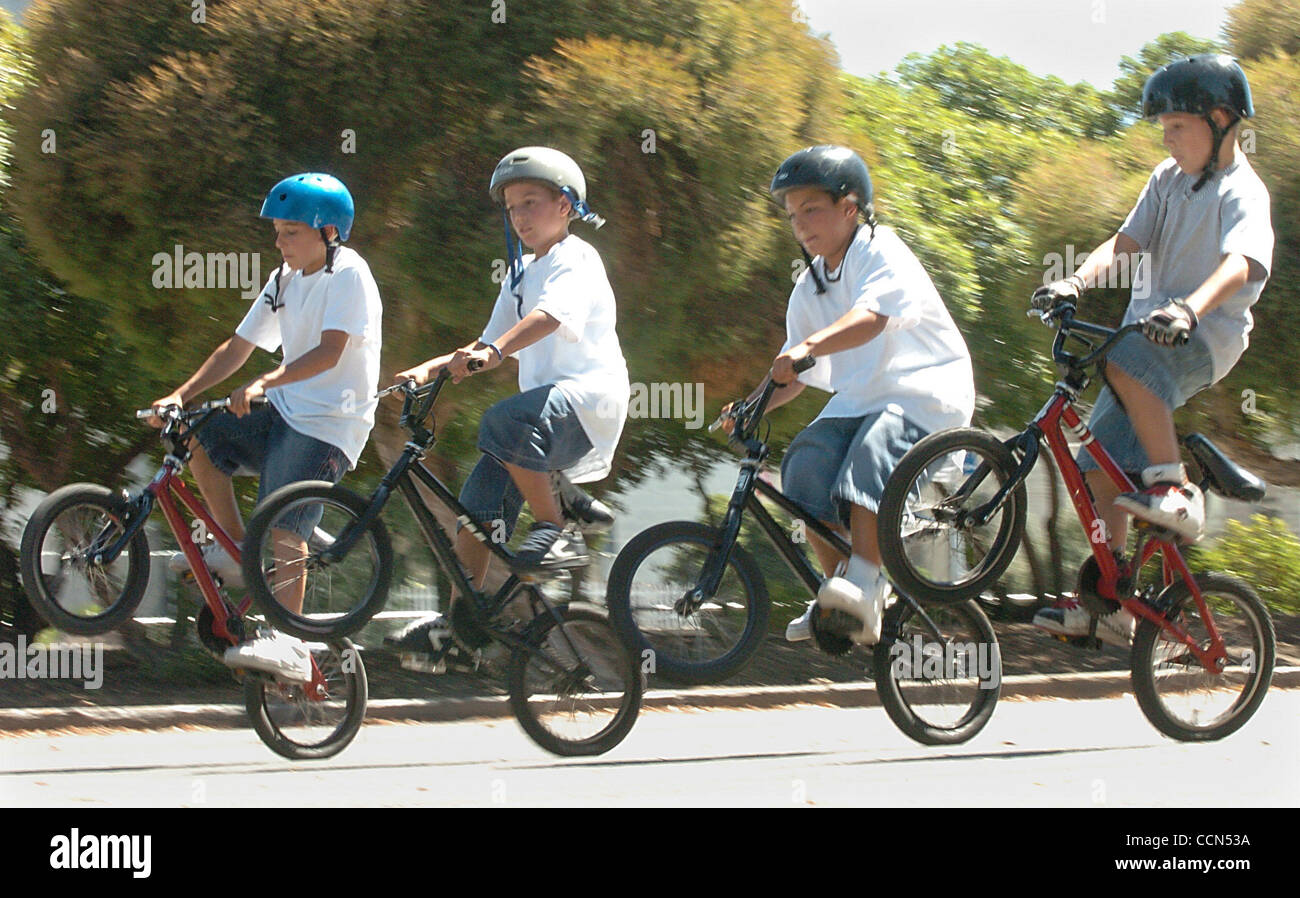 Four boys engage in a "wheelie " contest as they bike Monday, August 9 ...