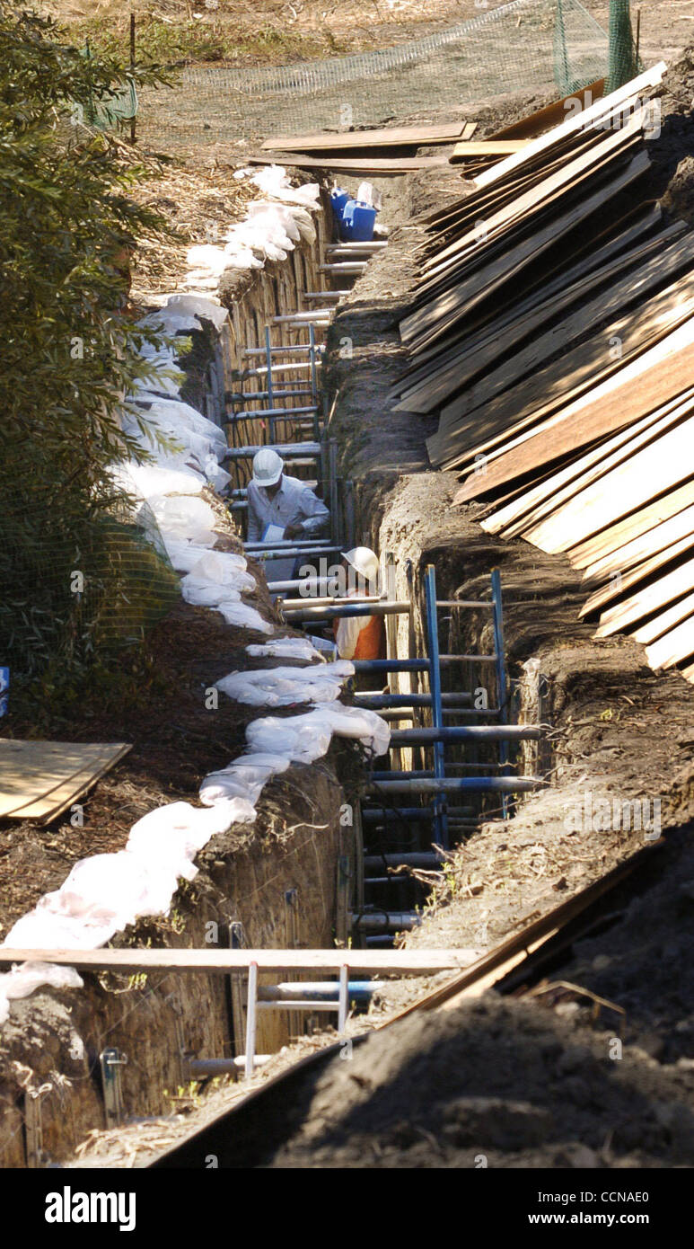 Geologist study the walls of a 16 ft deep trench that is being studied ...