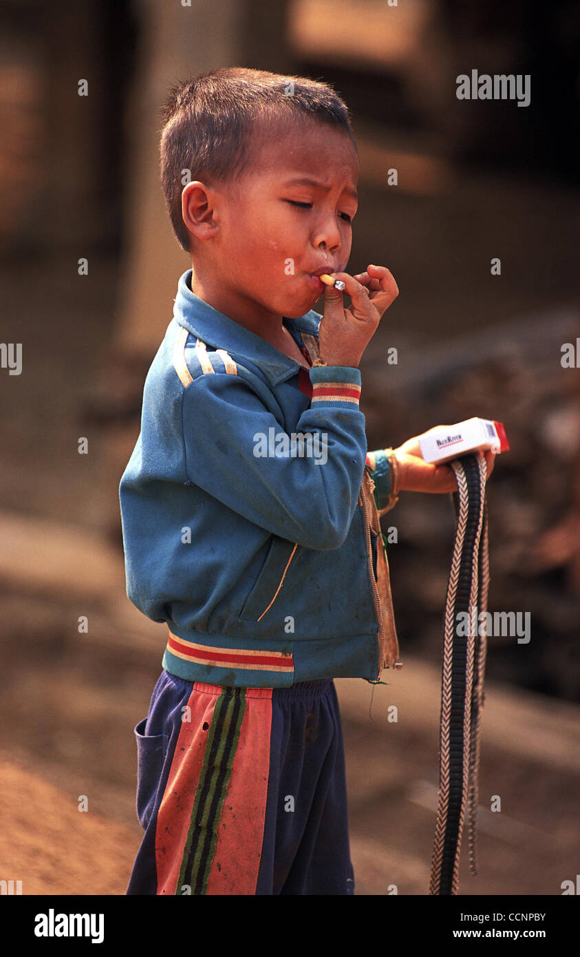 LAOS Young Hmong boy dragging on a cigarette in a poor village. Photo ...