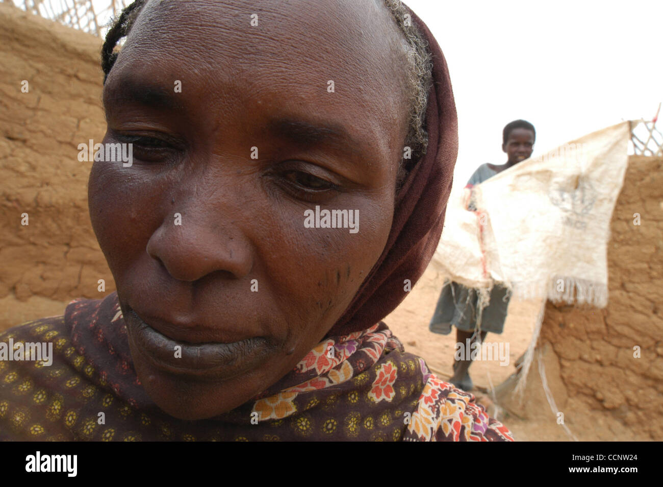 July 16, 2004, Touloum, Chad - A young boy looks on as a woman, both ...