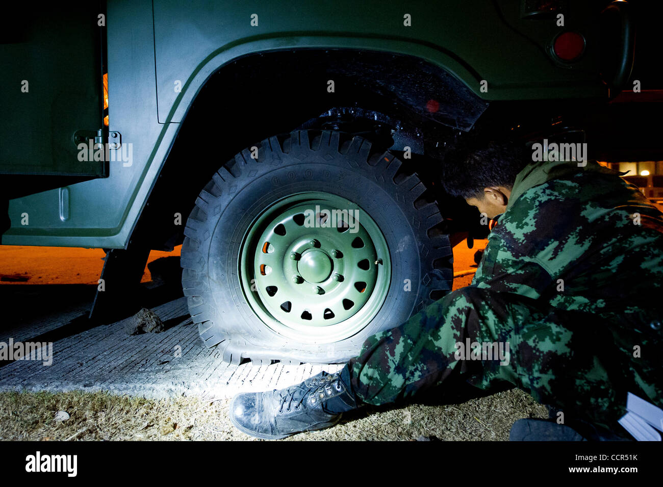 Thai soldiers fix flat tire on their damaged Humvee which park inside ...