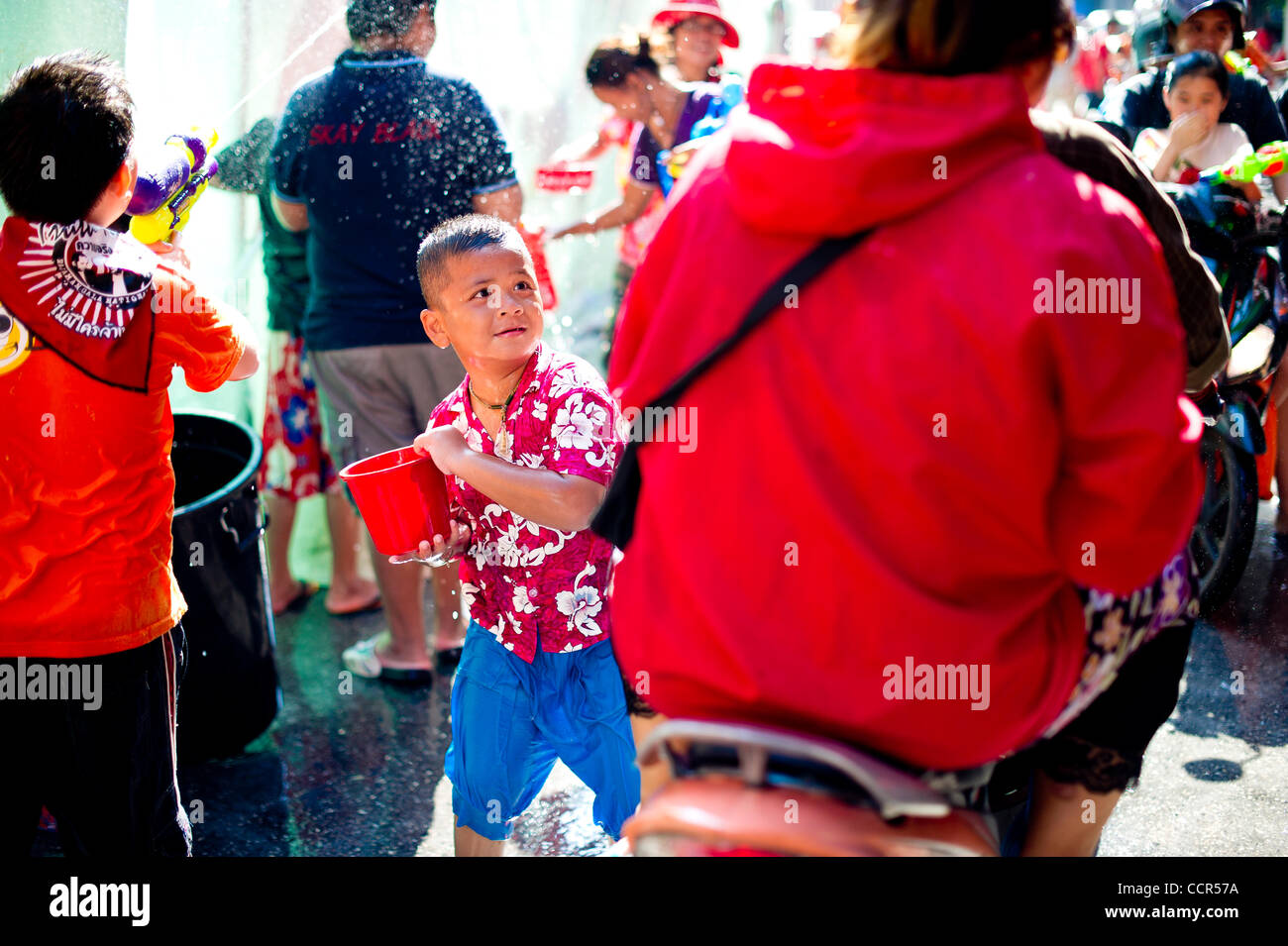Red Shirts splash passing by motorist with water during the Songkran ...