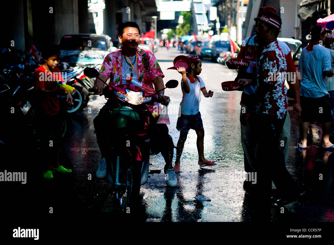 Red Shirts splash passing by motorist with water during the Songkran ...