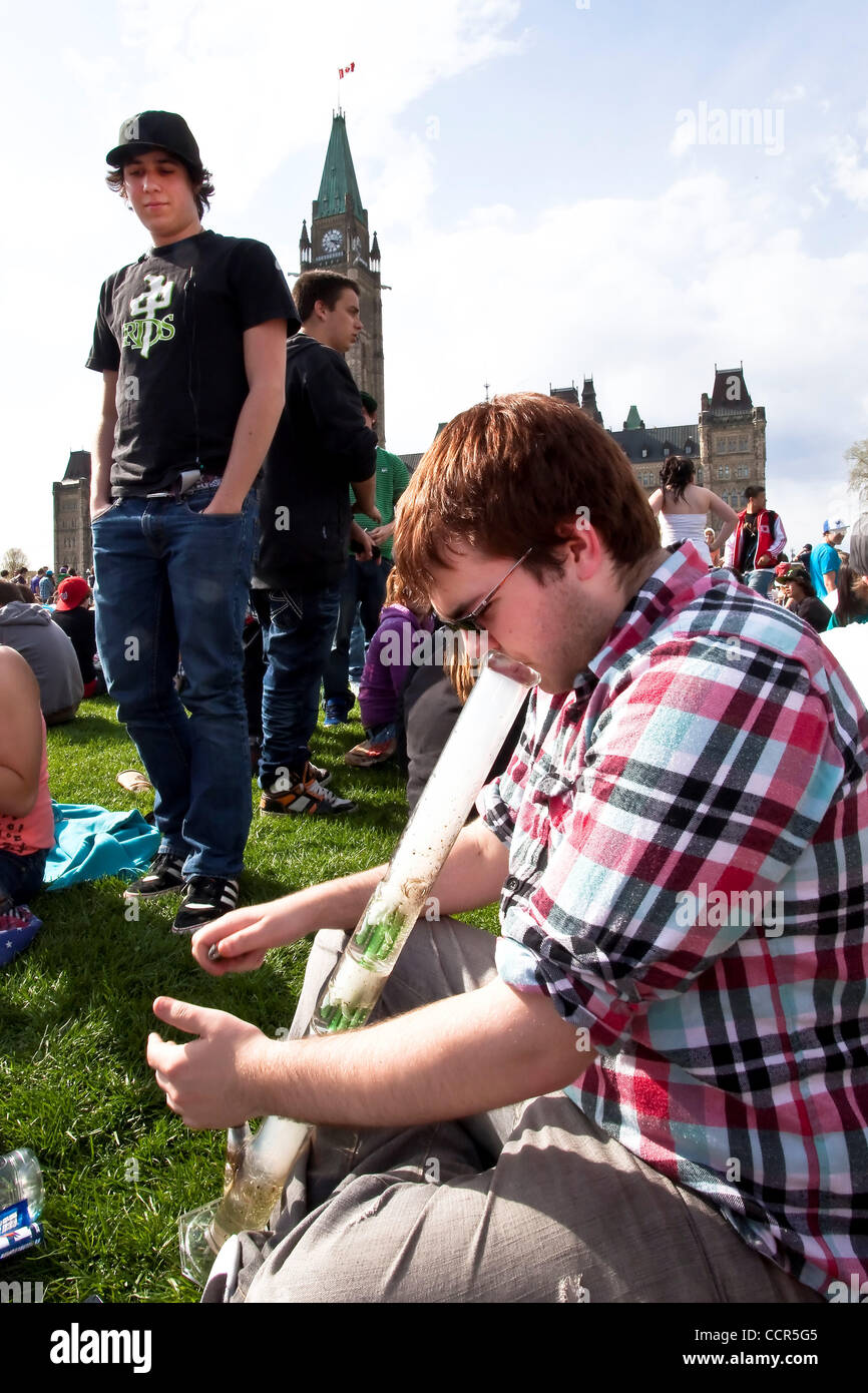 A young man smokes from a bong while his friend watches during the 420 ...