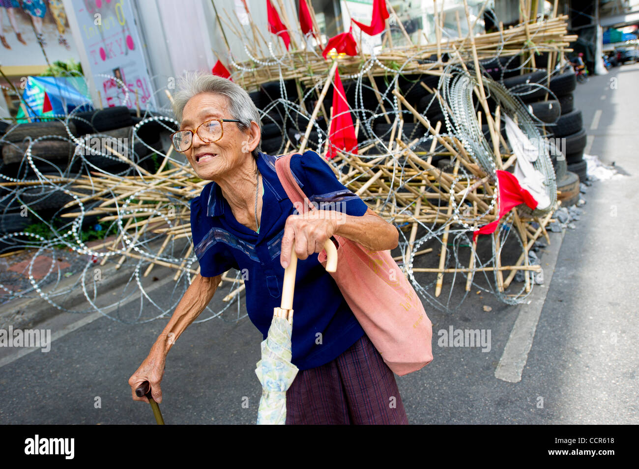 An elderly women walks in front of Red Shirts' barrier of tires ...
