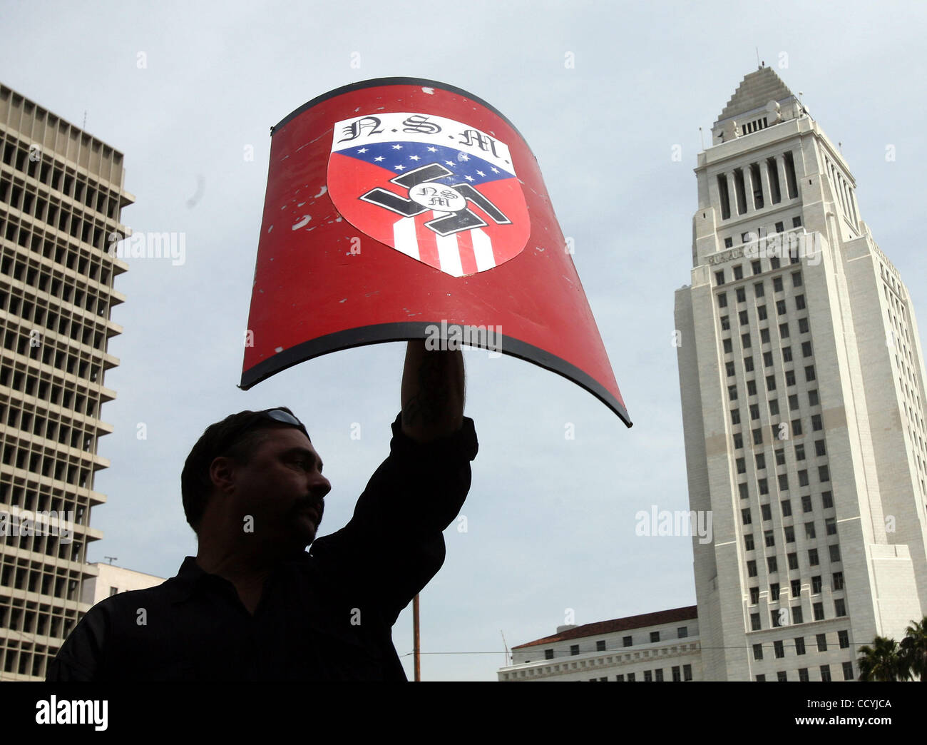 A member of the American National Socialist Movement rises a shield to ...