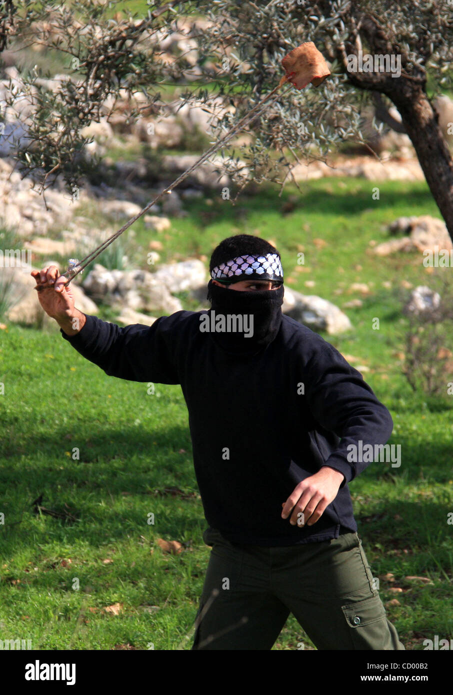 A Palestinian youth uses a sling to hurl stones towards Israeli ...