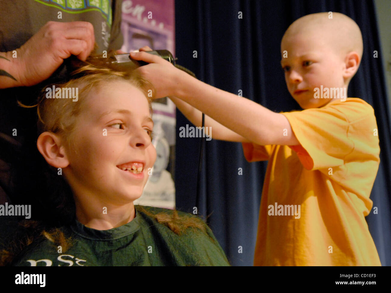 From left, Tanner Reed, 8, gets his head shaved by Chase Starr, 8 ...