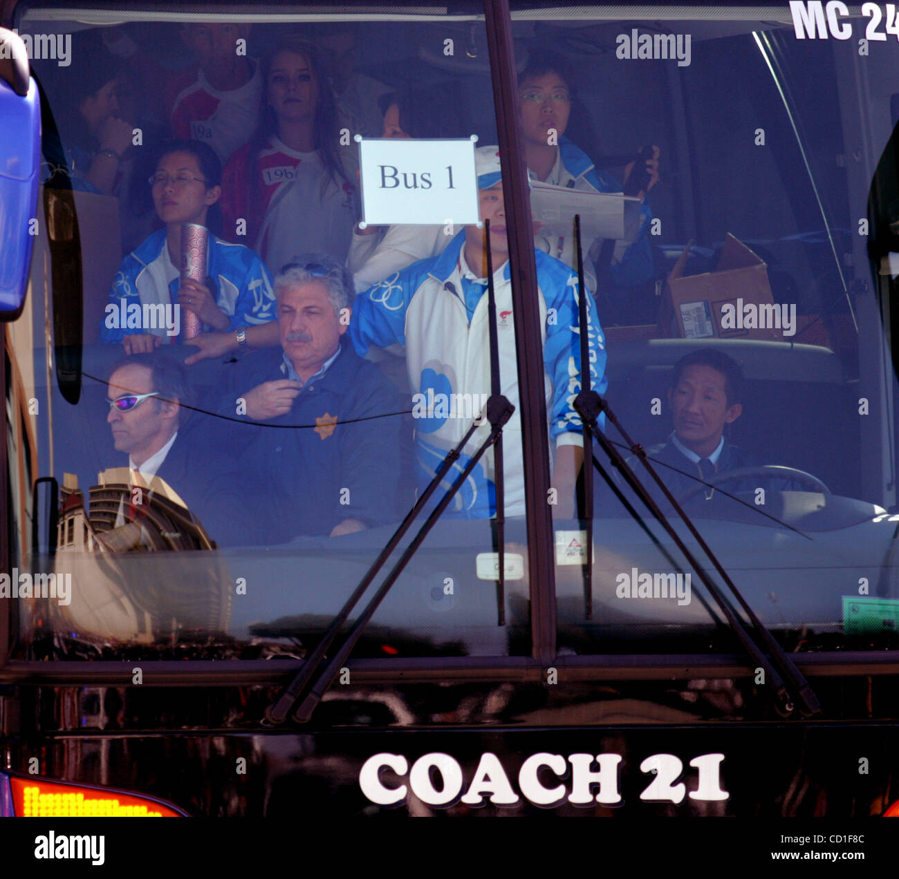 Olympic torch relay runners watch the crowd as they are transported by ...