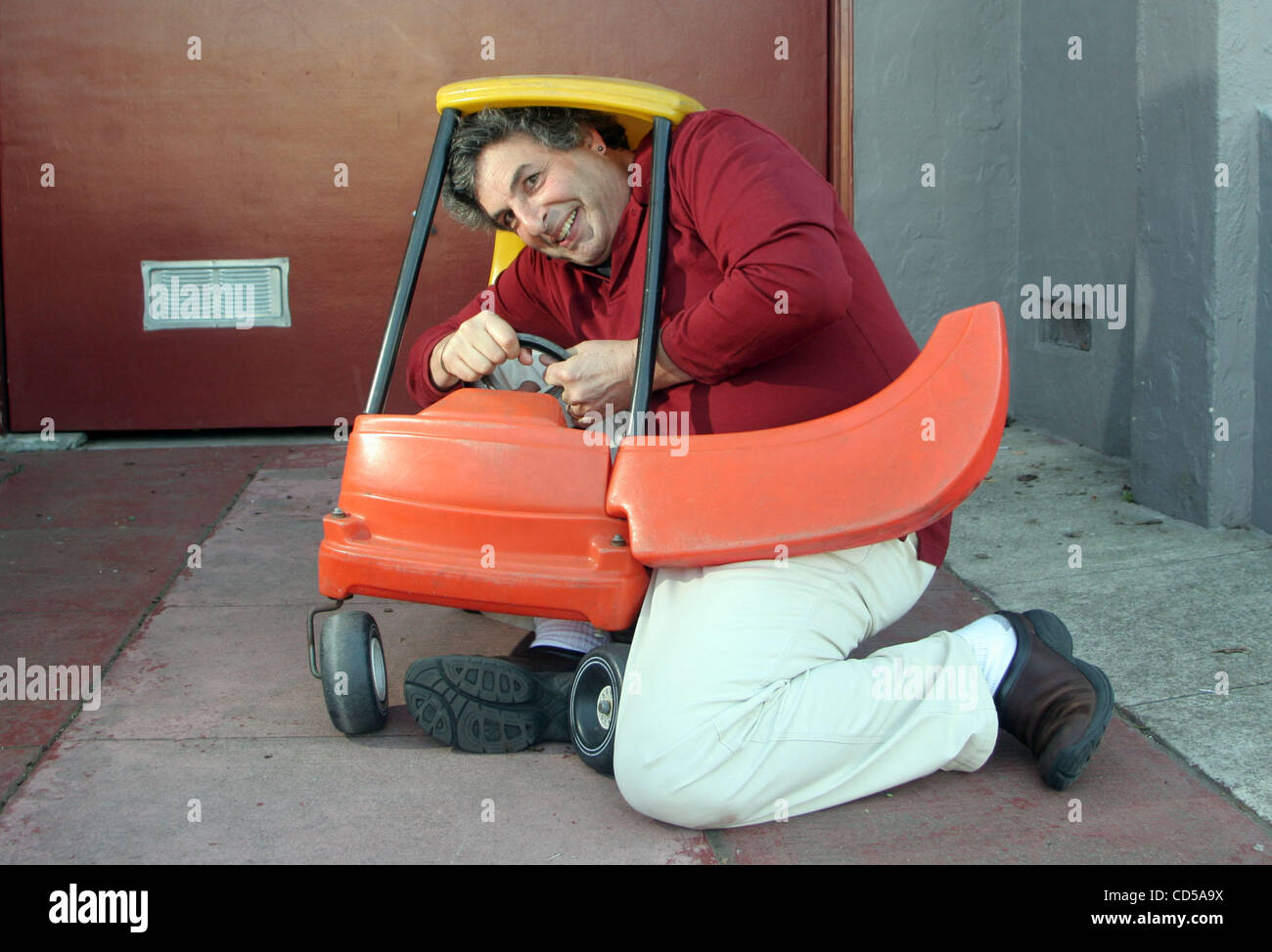 Jeff Raz, a professional clown, squeezes into a toy car at his home in ...