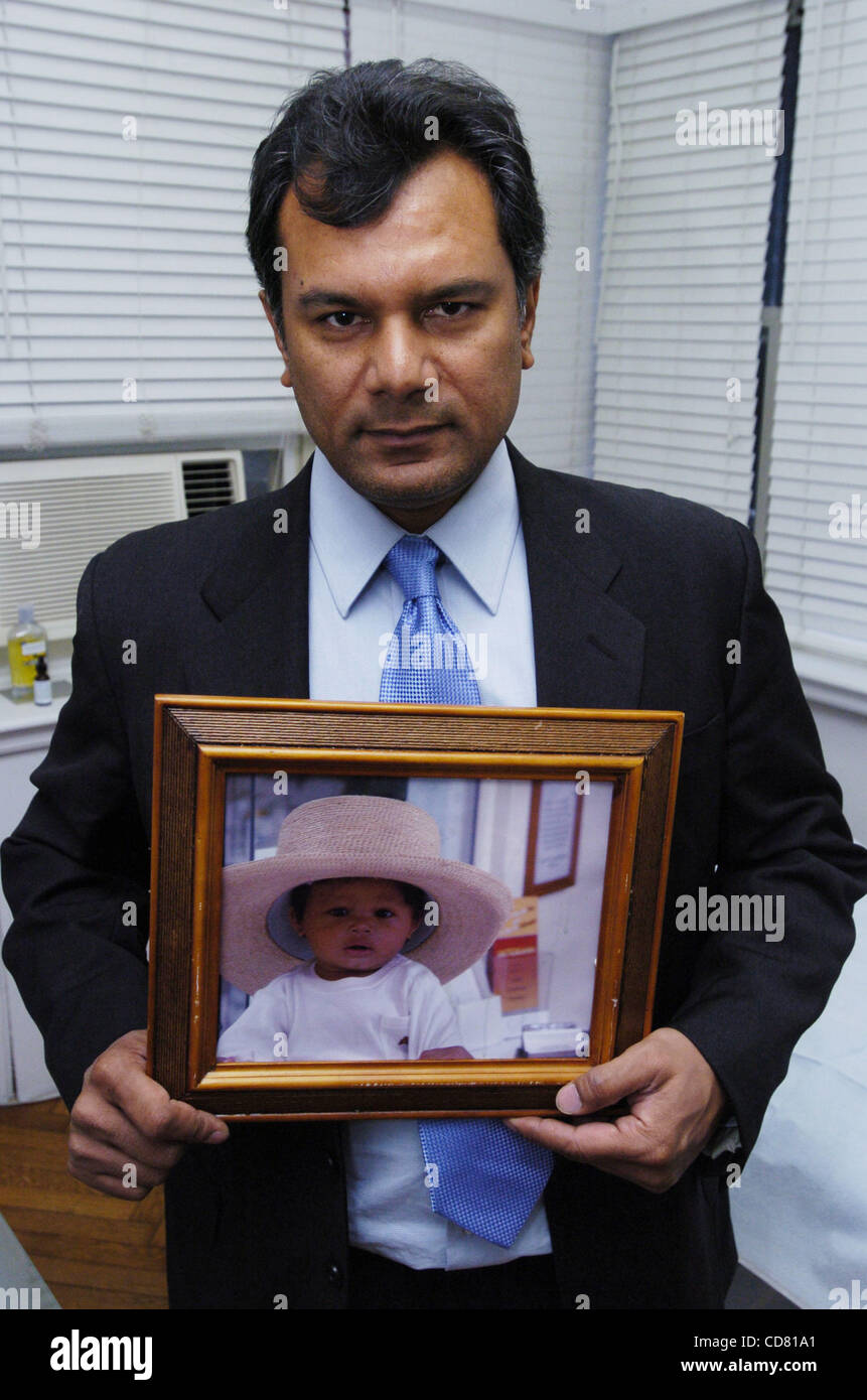 Dr. Lionel Bisoon in his office on W 74th Street, holding a photo of ...