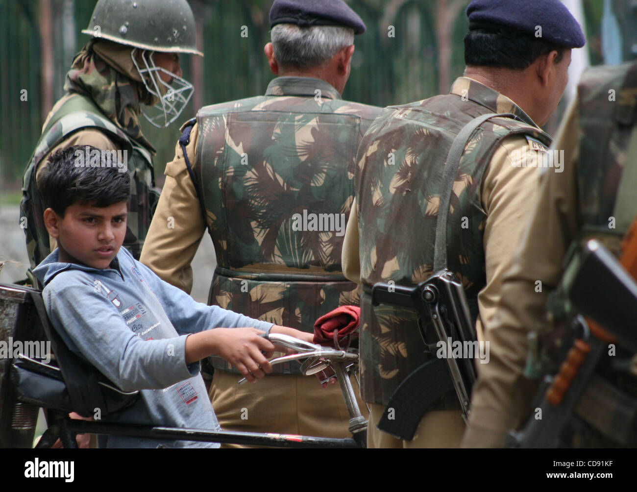 kashmiri muslim boy cross with his bicycle the road as indian solders ...