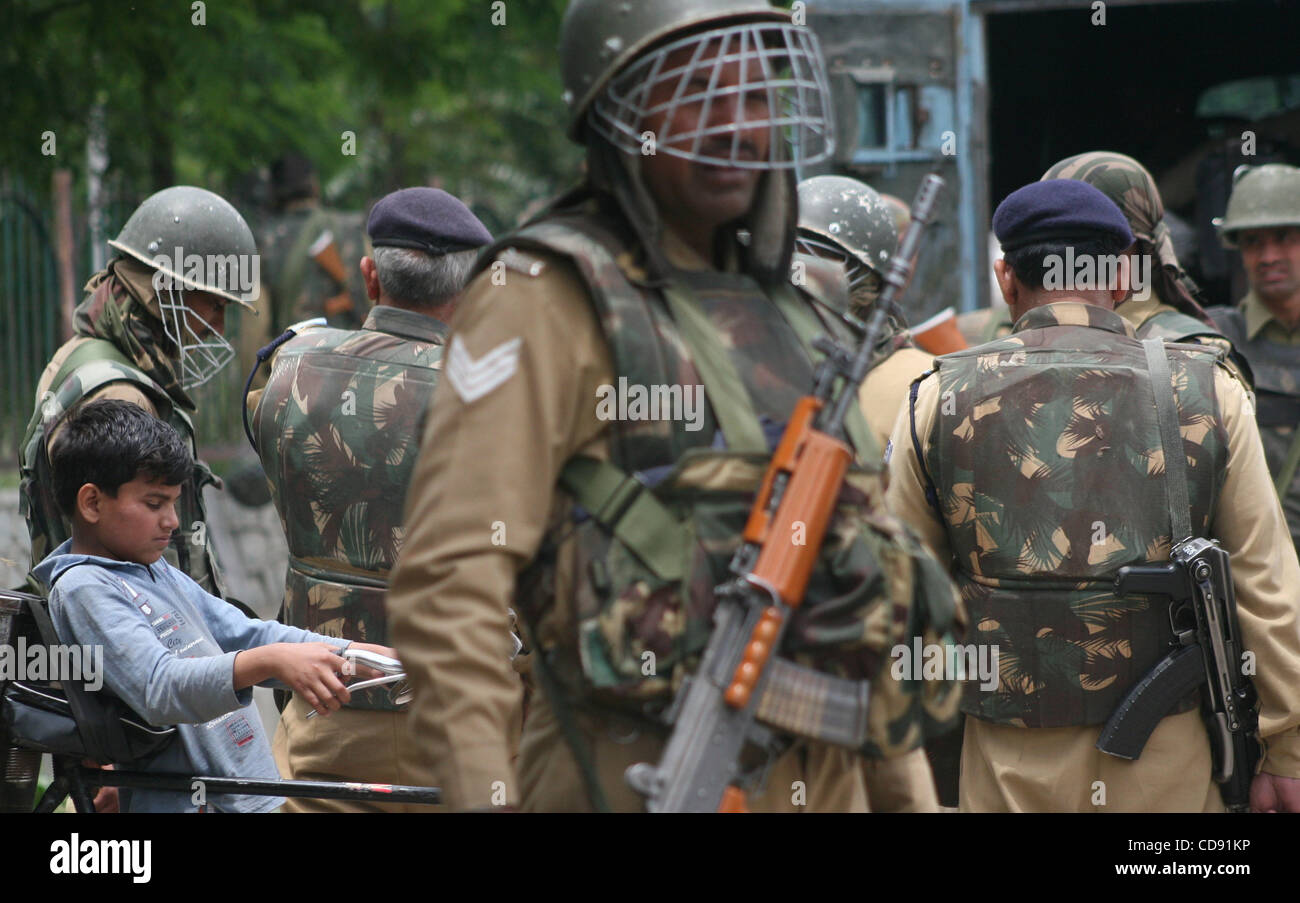 kashmiri muslim boy cross with his bicycle the road as indian solders ...