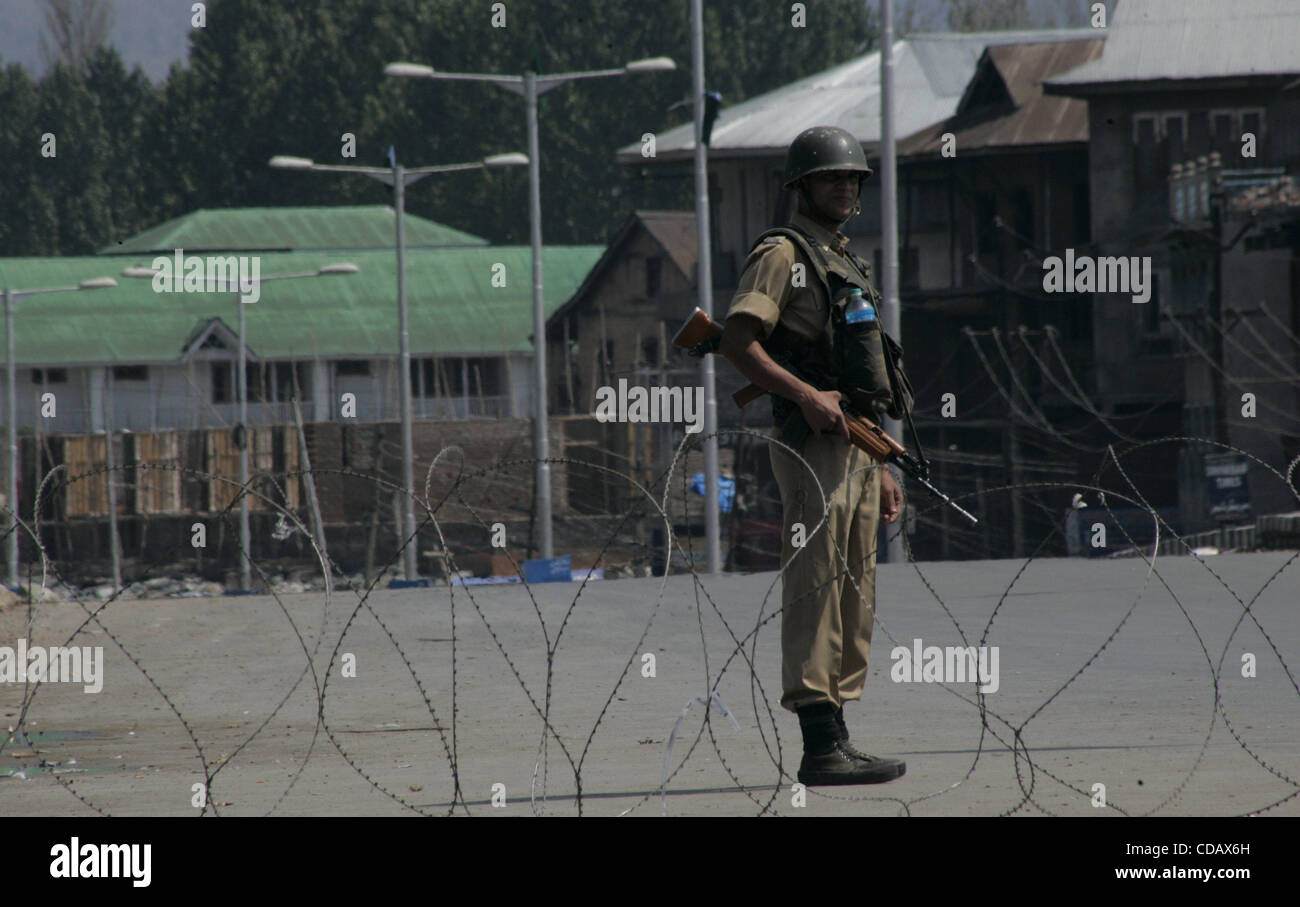 An Indian paramilitary soldier stands guard near barbed wire during a ...