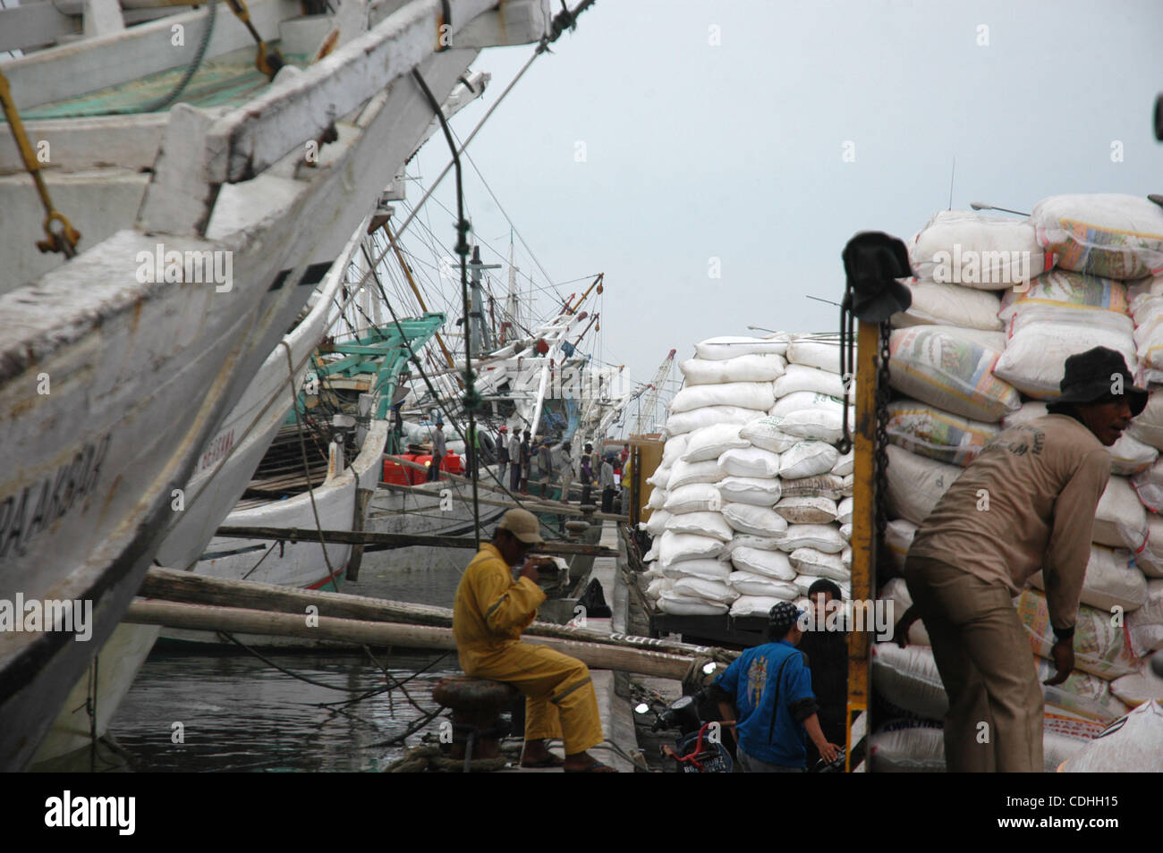 Workers load sacks of rice onto a traditional cargo ship for domestic ...