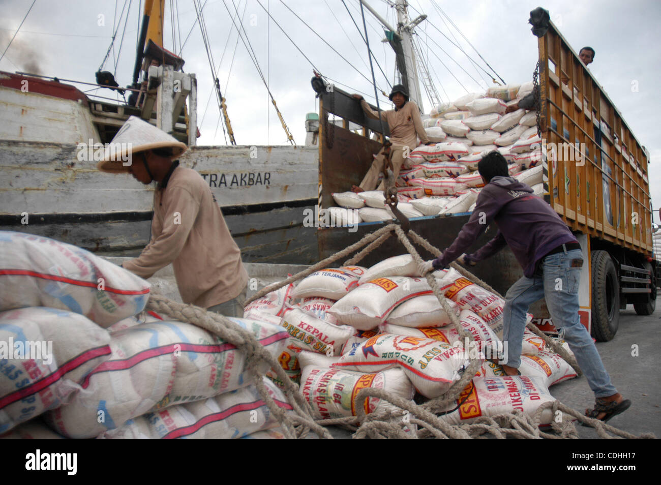 Workers load sacks of rice onto a traditional cargo ship for domestic ...