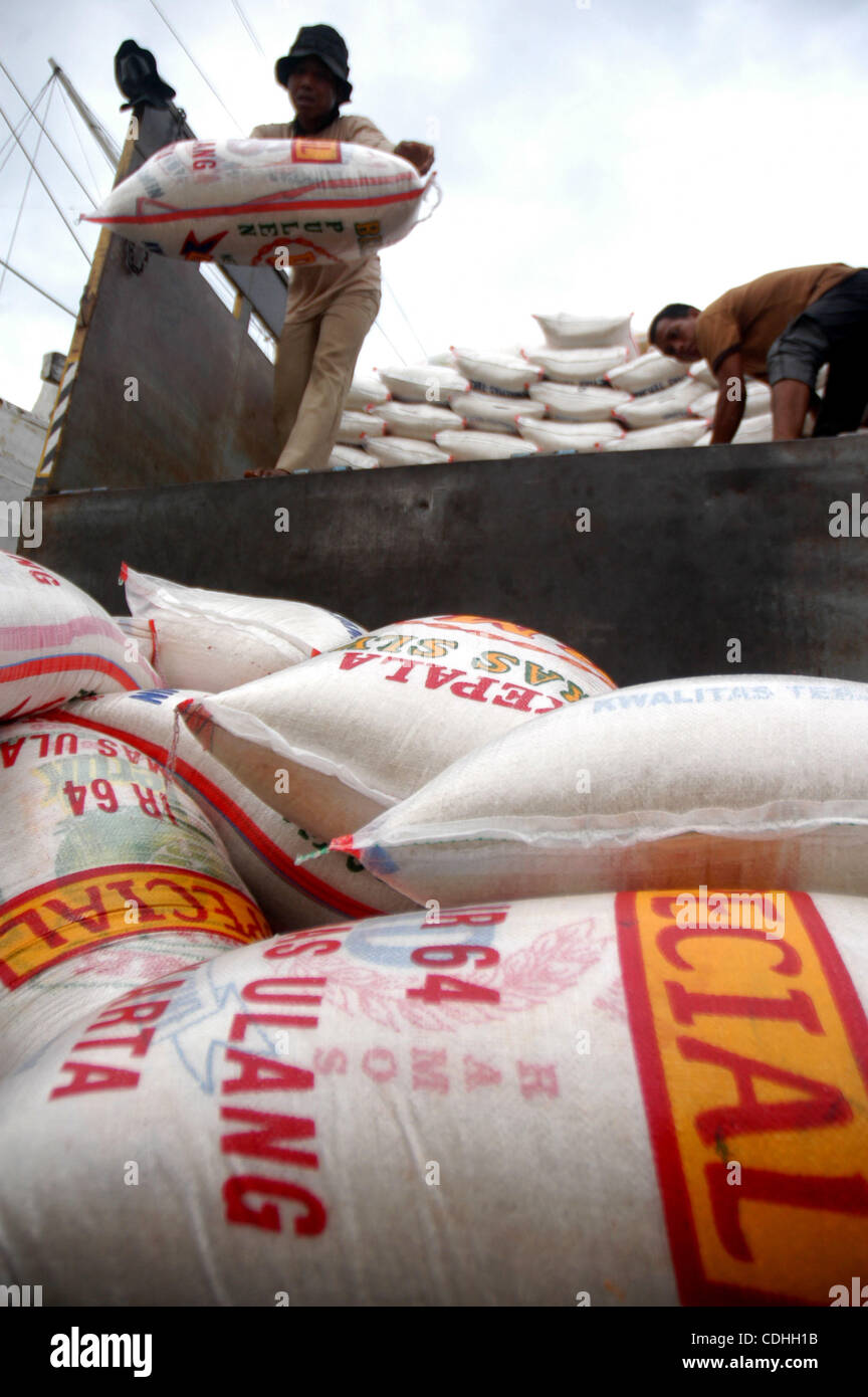 Workers load sacks of rice onto a traditional cargo ship for domestic ...