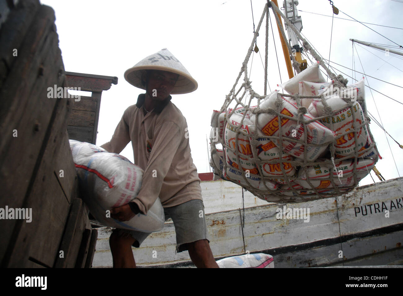 Workers load sacks of rice onto a traditional cargo ship for domestic ...