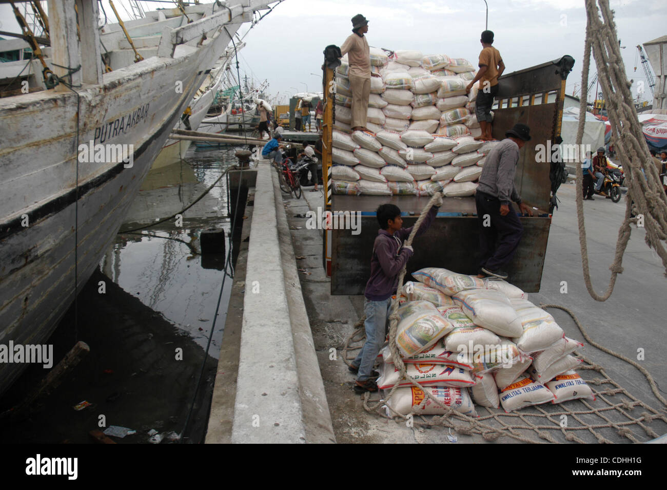 Workers load sacks of rice onto a traditional cargo ship for domestic ...