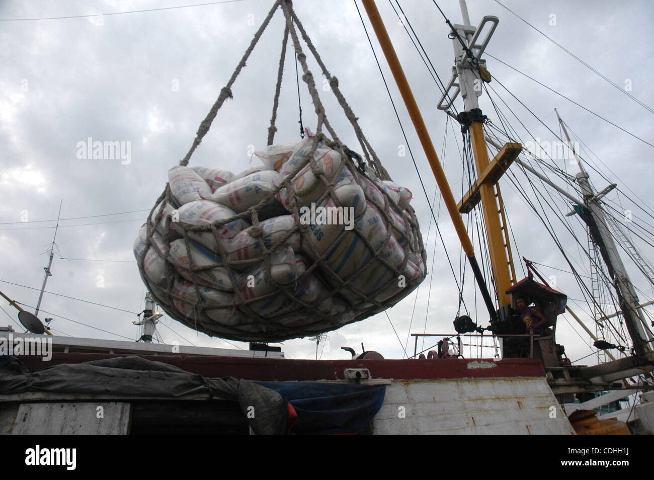 Workers load sacks of rice onto a traditional cargo ship for domestic ...