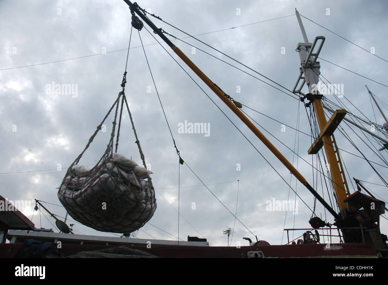 Workers load sacks of rice onto a traditional cargo ship for domestic ...