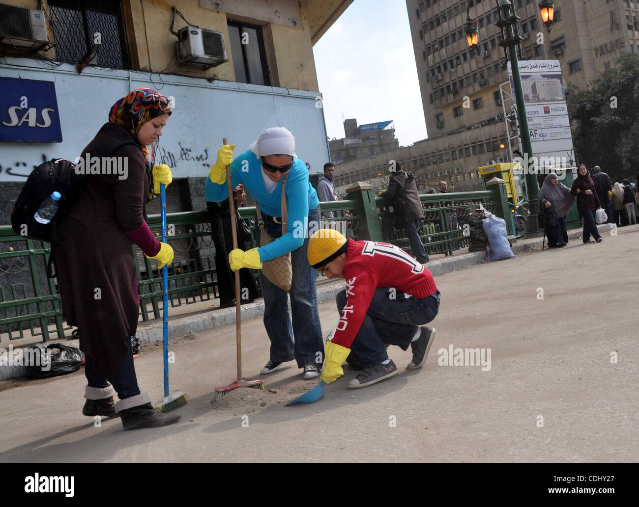 Egyptians clean up garbage and rocks from a street near Tahrir Square ...