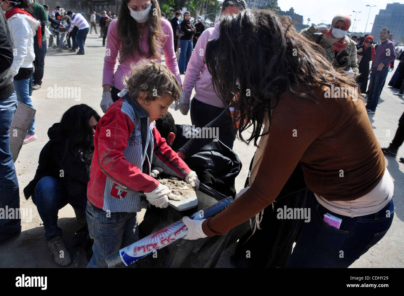 Egyptians clean up garbage and rocks from a street near Tahrir Square ...