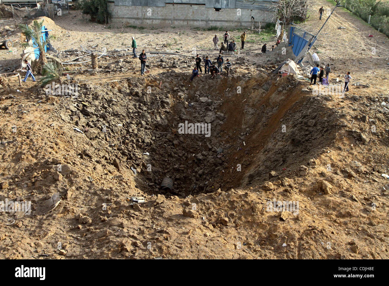 Palestinians stand next to a crater left after a missile fired from an ...