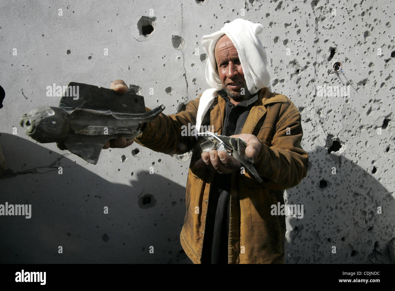 A Palestinian man carries shrapnel that hit house by Israeli artillery ...