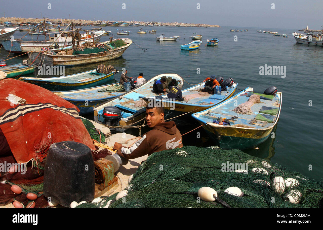 Palestinian fisherman fixes his fishing nets at the port in Gaza City ...