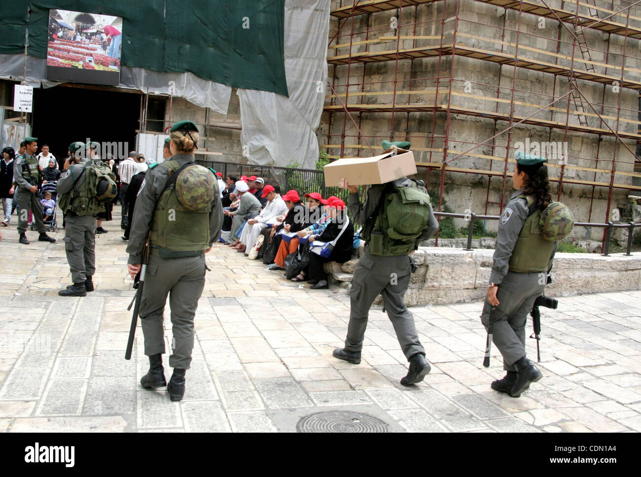 Palestinians walk past an Israeli police officers as they stand guards ...